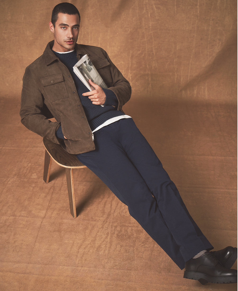 Man sitting on a chair holding a book against a brown textured background