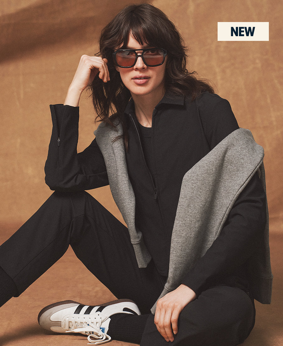 Person wearing sunglasses and a black outfit with a gray sweater draped ...